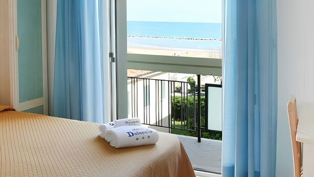 Quarto de hotel com cama, varanda e vista para a praia.