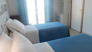 Quarto de hotel com duas camas, televisão, guarda-roupa e porta.