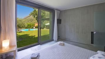 Quarto com uma grande porta de vidro que dá para uma piscina e um jardim.