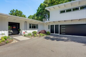 Uma casa moderna de dois andares com garagem, varanda frontal e jardim ajardinado.