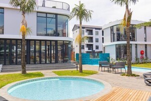 Um edifício moderno com piscina, área de estar ao ar livre e palmeiras.