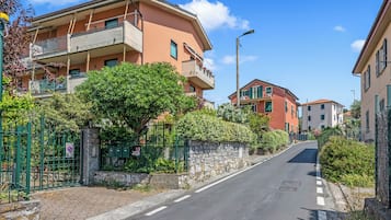Rua residencial com edifícios altos, portão fechado e céu claro.