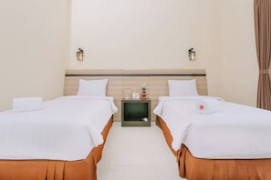 Quarto de hotel com duas camas, uma mesa de cabeceira, um abajur e uma cortina.
