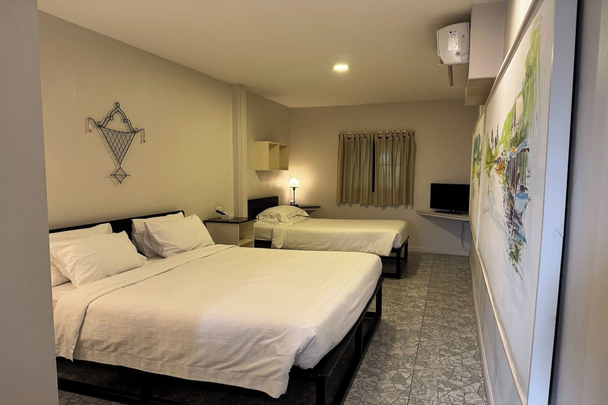 Quarto de hotel com duas camas, televisão, luminária e um quadro na parede.