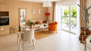 Uma sala de estar moderna com sofá, cadeiras, uma mesa de jantar e uma área de cozinha.
