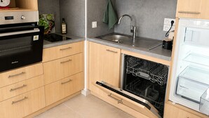 Uma cozinha moderna com armários de madeira, forno embutido, pia e lava-louças.