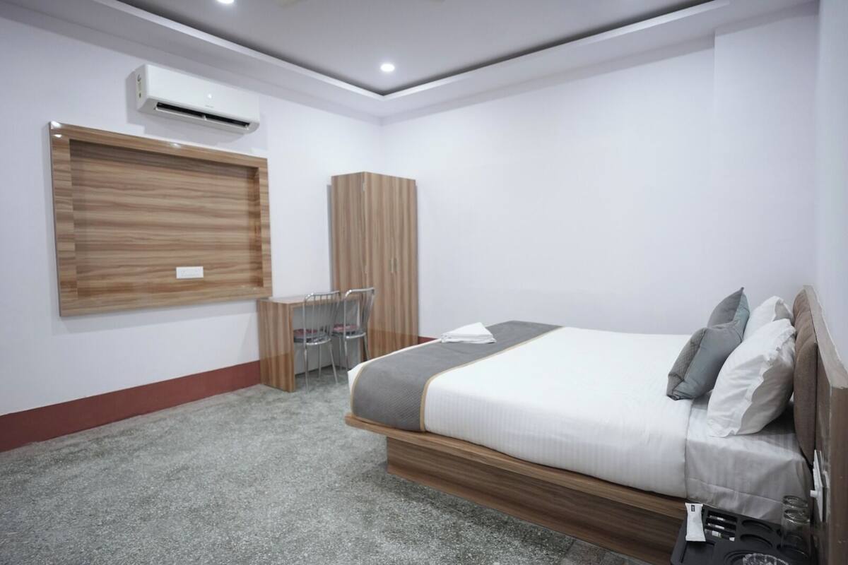 Quarto com cama, escrivaninha, cadeira, guarda-roupa e ar condicionado.