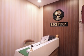 Uma mesa de recepção com uma placa indicando 'RECEPTION' e 'SUBARNREKHA HERITAGE' em cima.