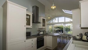 Cozinha moderna com armários brancos, uma janela ampla e vista para o exterior.