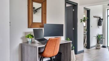Um espaço de escritório moderno com uma mesa, laptop, cadeira e um espelho.