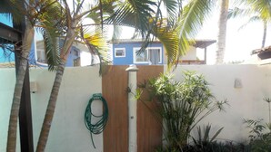 Uma área residencial com uma casa azul, uma parede branca e uma cerca de madeira.