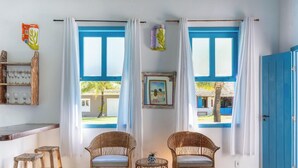 Quarto com duas cadeiras de vime, uma mesa pequena e um balcão.