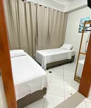 Quarto com duas camas, moldura de porta de madeira, parede branca e um quadro.