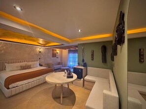 Uma sala de estar moderna com um sofá, uma mesa de centro redonda e uma cama com cabeceira.