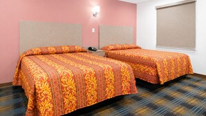 Quarto de hotel com duas camas, telefone, luminária e janela com persiana.
