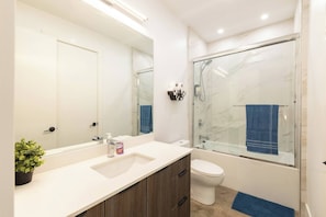 Um banheiro moderno com box de vidro, pia branca e vaso sanitário.