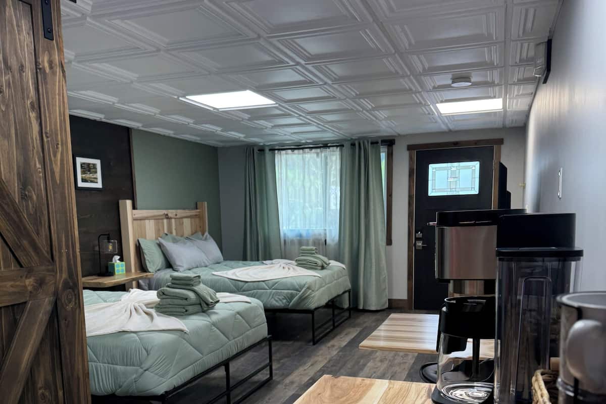 Quarto com duas camas, uma máquina de café e uma mesa de madeira.