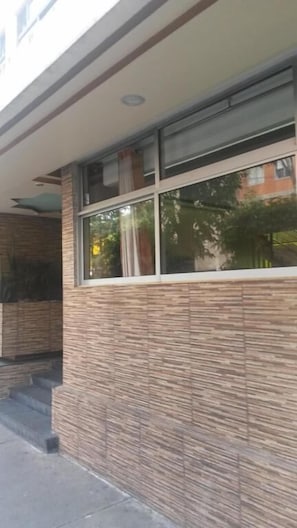 Edifício com fachada moderna, grandes janelas e escadaria visível que leva a uma entrada.