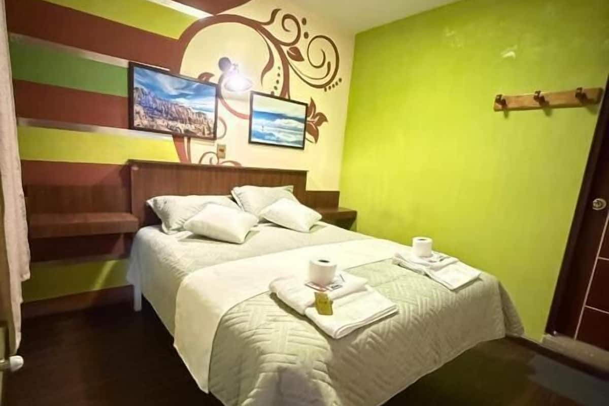 Um quarto com uma cama, uma televisão e uma parede com um desenho decorativo.