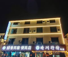 Um edifício com vários andares e sinalização iluminada para um hotel e um restaurante.