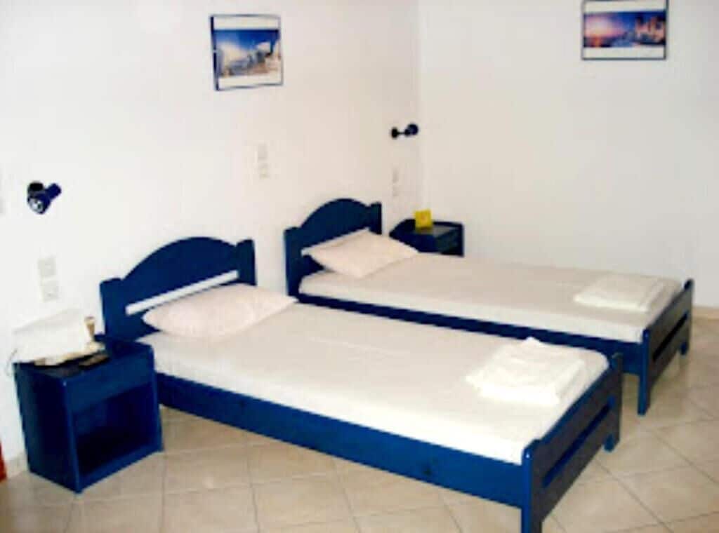 Quarto com duas camas, uma mesinha de cabeceira e um quadro pendurado na parede.