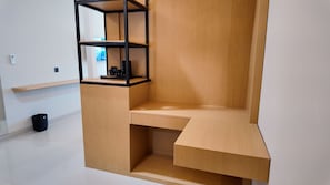 Quarto minimalista com escrivaninha embutida, estante preta e lixeira preta.
