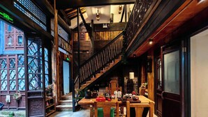Interior em madeira com escada, uma mesa com cadeiras e vista para o exterior.