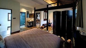 Quarto com uma cama grande, teto de madeira e vista para o exterior.