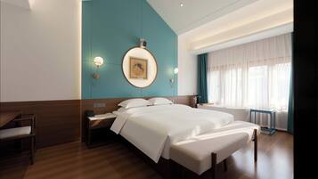 Quarto de hotel moderno com uma cama grande, uma mesa, uma cadeira e uma janela com cortinas.