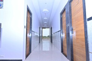 Um corredor com portas, luminária no teto e piso de azulejos.