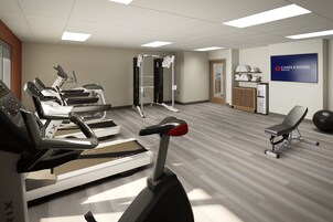 Centro de fitness com esteiras, equipamento de musculação e um aviso fixado na parede para Candlewood Suites.