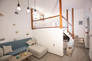Um interior moderno com um sofá, uma mesa de centro, uma escada e uma área de cozinha.