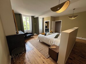 Quarto moderno com cama, mesas de cabeceira, escrivaninha e cadeira.