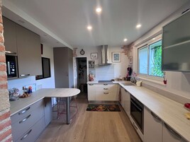 Uma cozinha compacta com forno embutido, micro-ondas e exaustor de aço inoxidável.