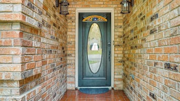Pareda de tijolos com uma porta, um arco decorativo e um tapete de entrada.