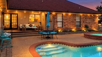 Um imóvel residencial com piscina, área de estar externa e fachada de tijolos.