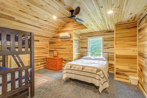 Quarto de cabana de madeira com cama, cômoda e janela.