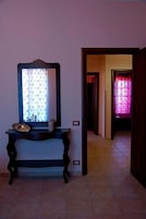 Um corredor com um aparador de madeira escura, um espelho e uma porta que dá para outro quarto.
