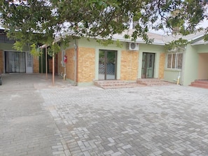 Um edifício com fachada de tijolos, porta verde e pequena varanda frontal.