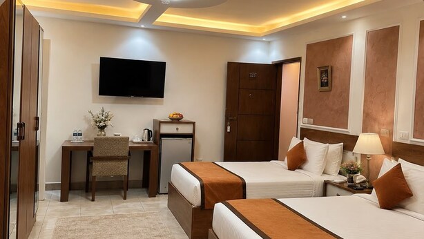 Quarto de hotel com duas camas, uma escrivaninha, uma televisão e uma porta com um número.