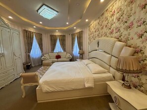 Um quarto espaçoso com uma cama grande, um espaço para sentar e um guarda-roupa.