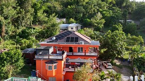 Um edifício de vários andares com painéis solares, uma varanda e um carro estacionado por perto.