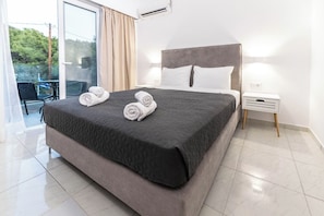 Quarto de hotel moderno com uma cama grande, uma mesa de cabeceira e vista para o exterior.