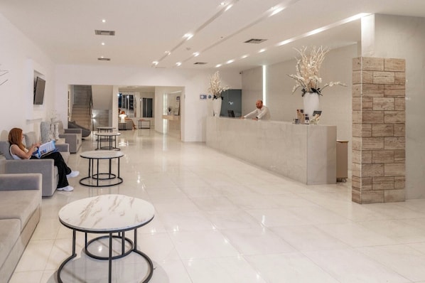 Um hall de hotel moderno com balcão de recepção, área de estar e chão de azulejos limpo.