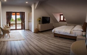 Quarto com cama grande, televisão e varanda com cortinas.