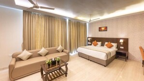Quarto de hotel moderno com sofá, cama, ventoinha no teto e pintura na parede.