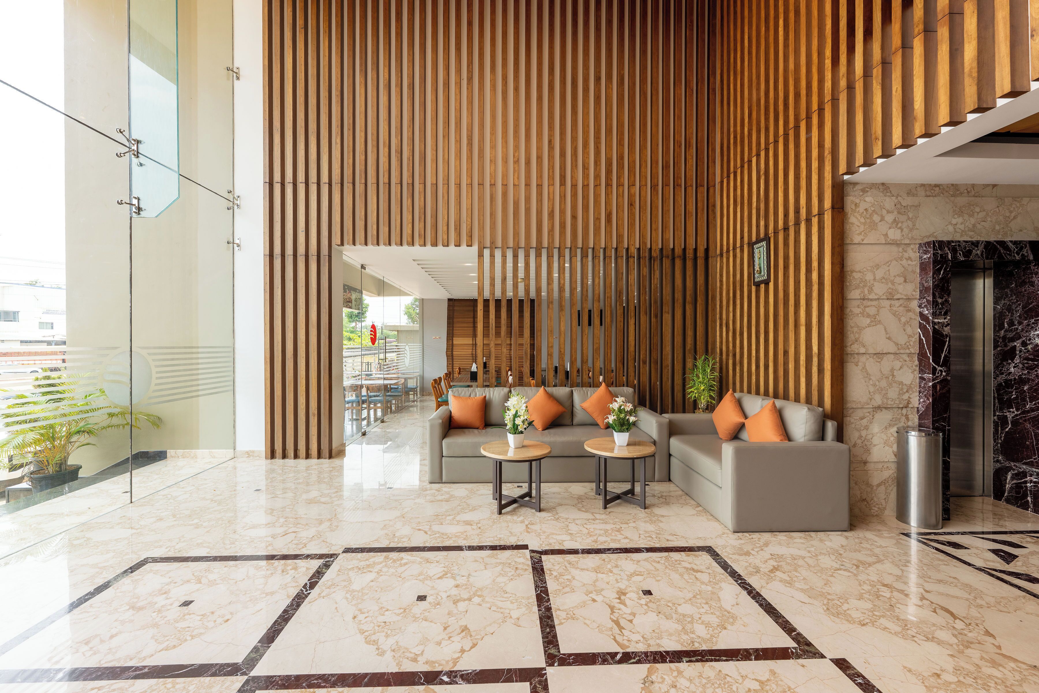 Um lobby moderno com balcão de recepção, área de estar e piso de mármore.