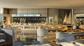 Um restaurante moderno com balcão central, diversas mesas de jantar e cozinha visível ao fundo.
