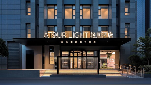 Entrada moderna de hotel com uma placa que diz 'ATOUR LIGHT'.