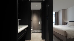 Quarto de hotel moderno com cama, banheiro com chuveiro e closet espaçoso.